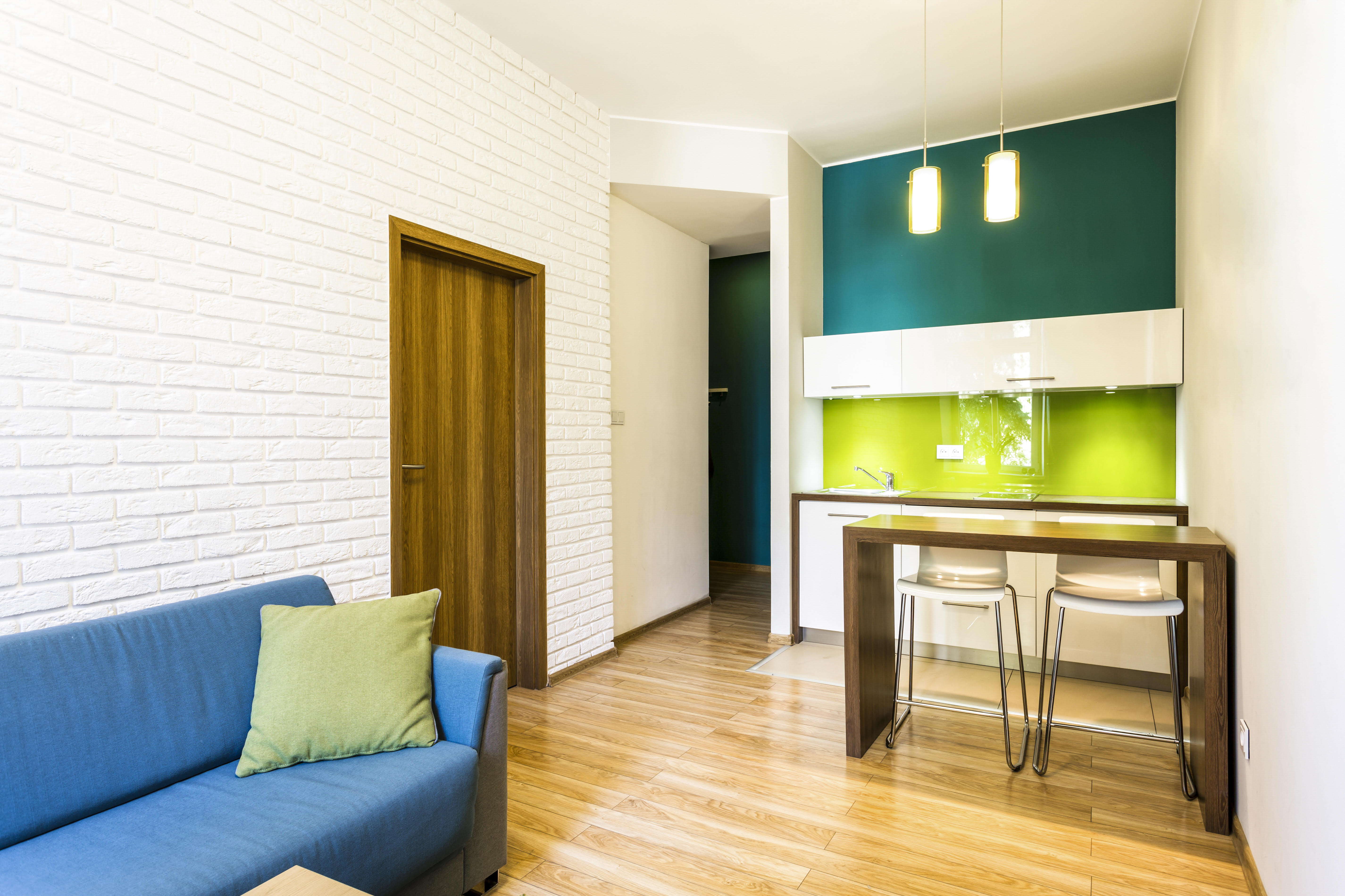 Small living room with brick wall and green kitchenette - Philly Happening